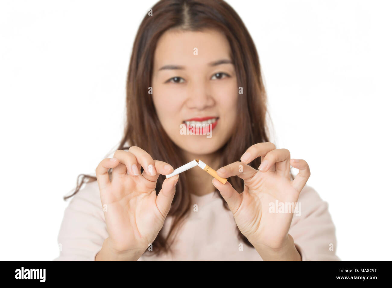 Beautiful Asian woman smiling while breaking a cigarette to quit ...
