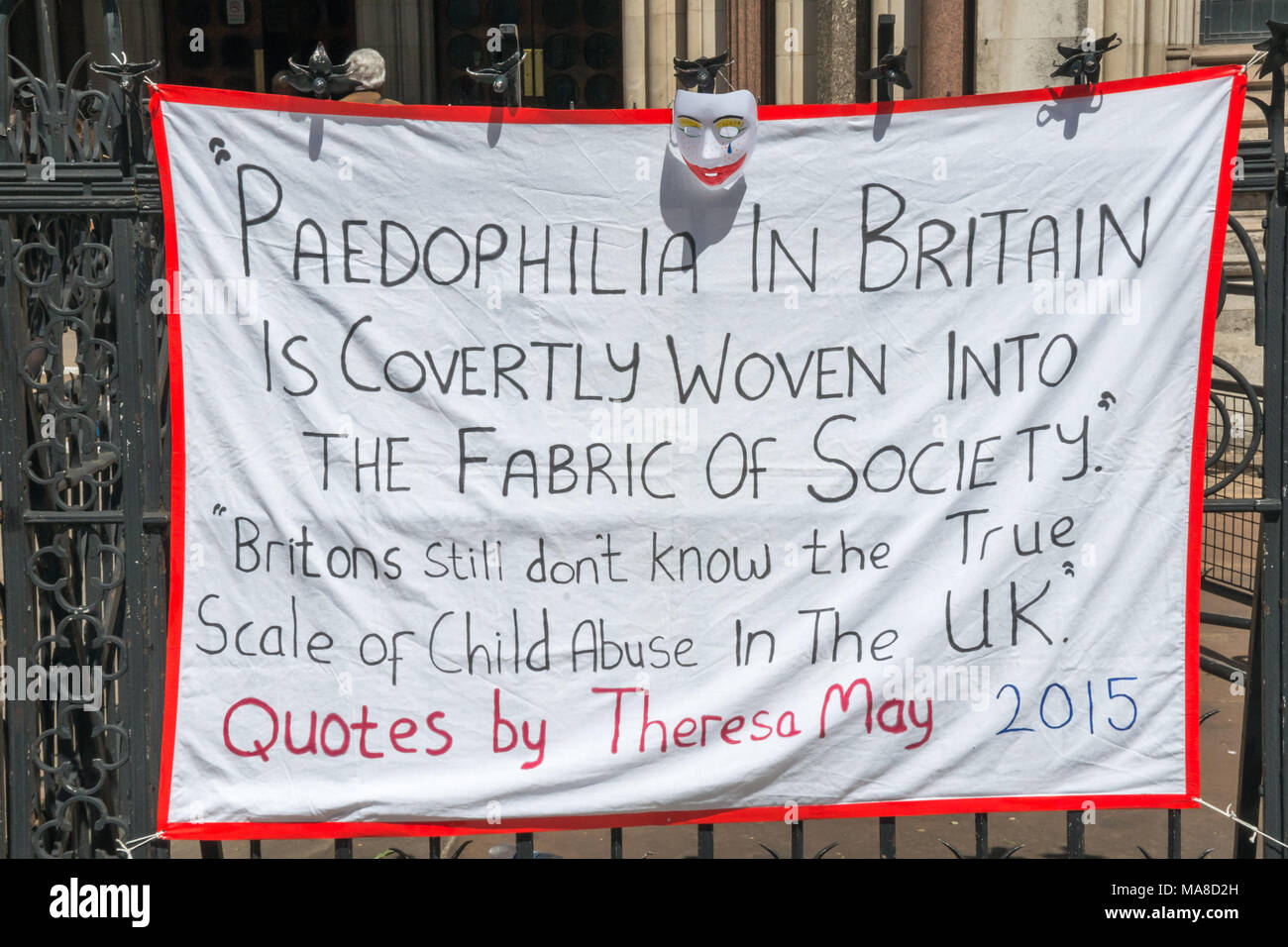 A banner and mask on the fence of the Royal Courts of Justice, London ...