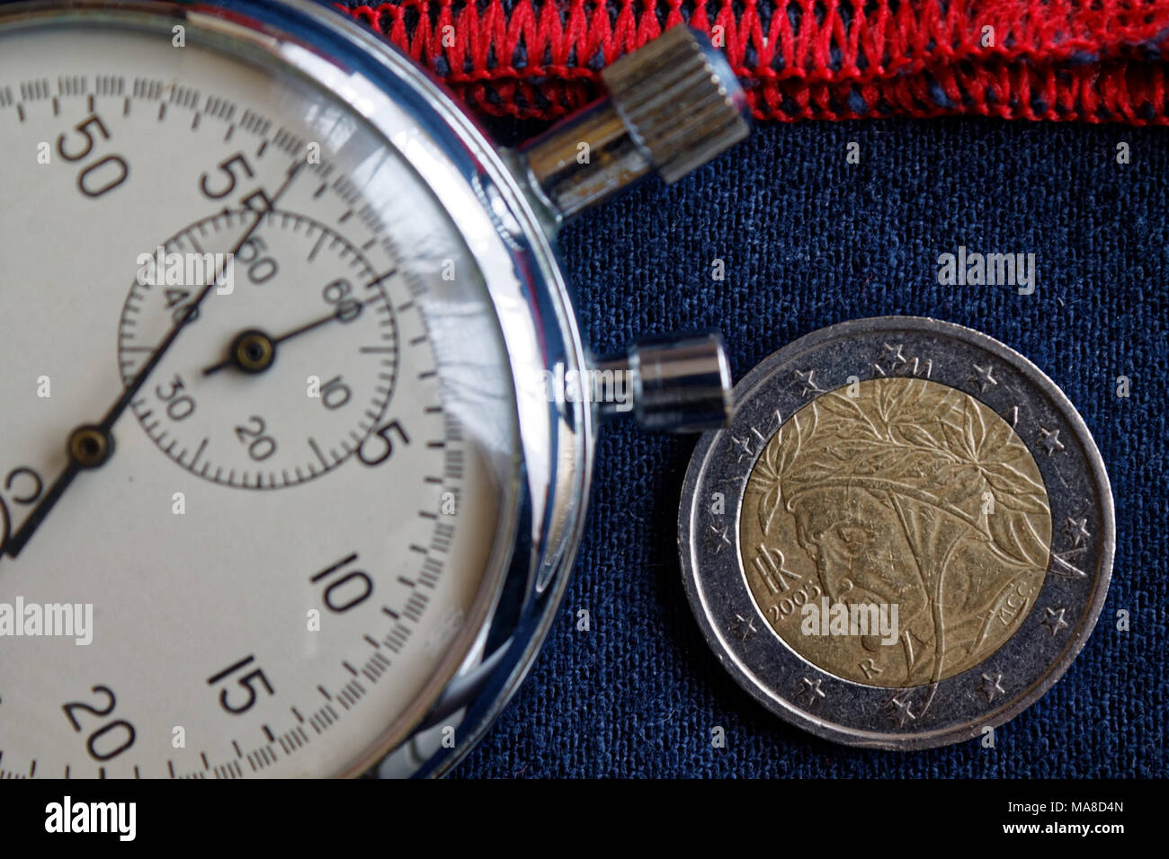 Euro coin with a denomination of 2 euro (back side) and stopwatch on ...