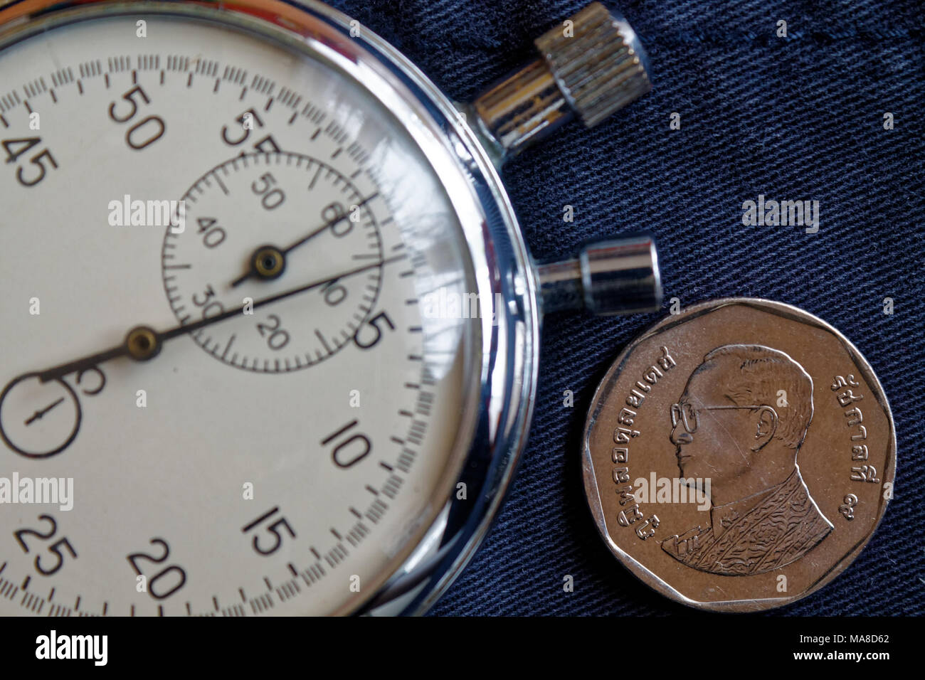 Thai coin with a denomination of 5 baht (back side) and stopwatch on ...