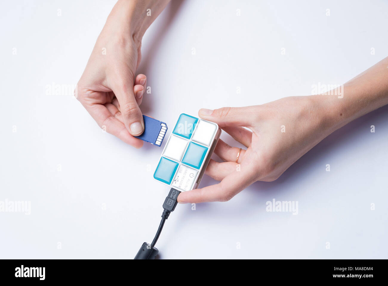 Hands of a girl inserting a memory card into a card reader on a white ...