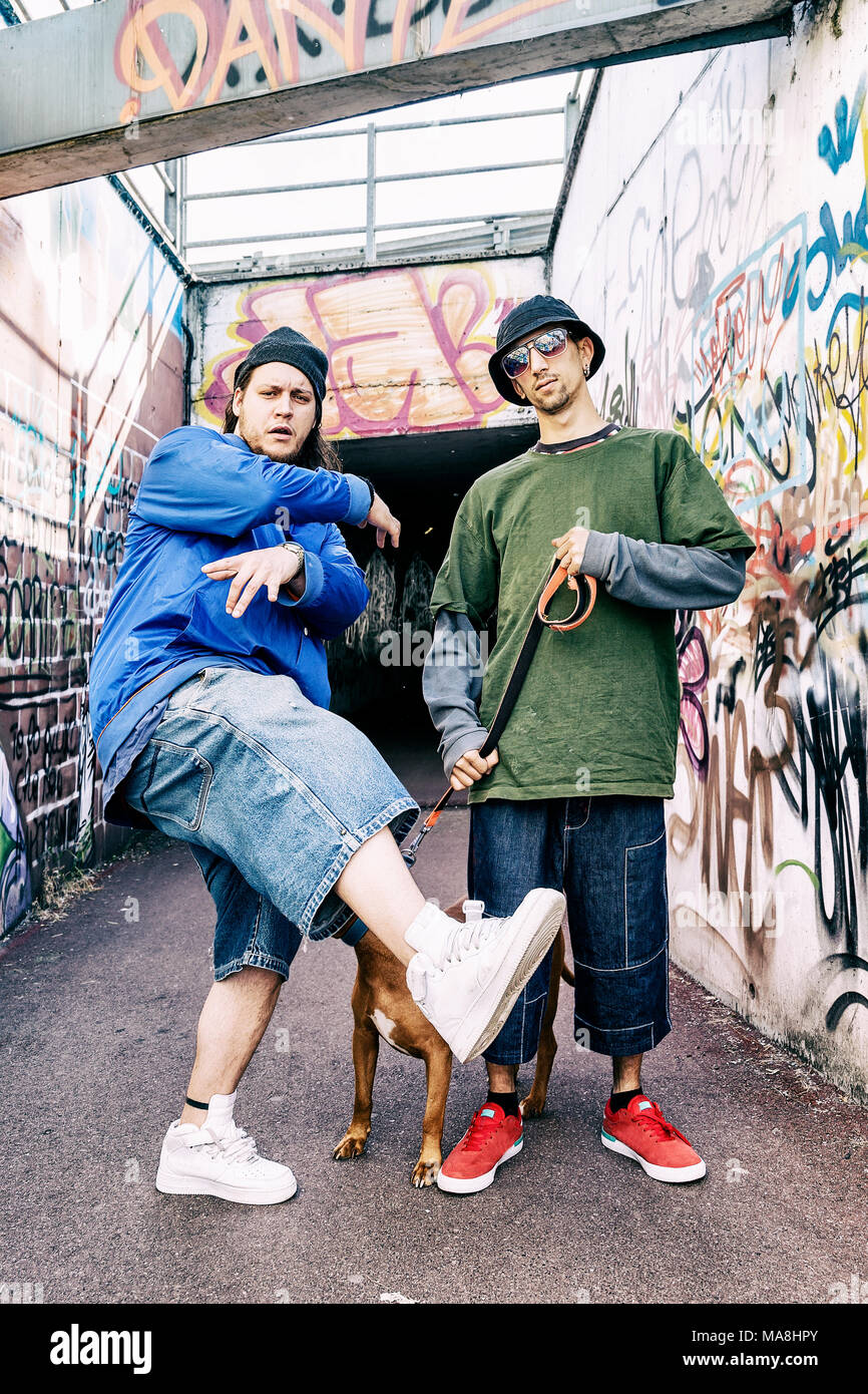 two rap singers with a dog in a subway with graffiti in the background ...