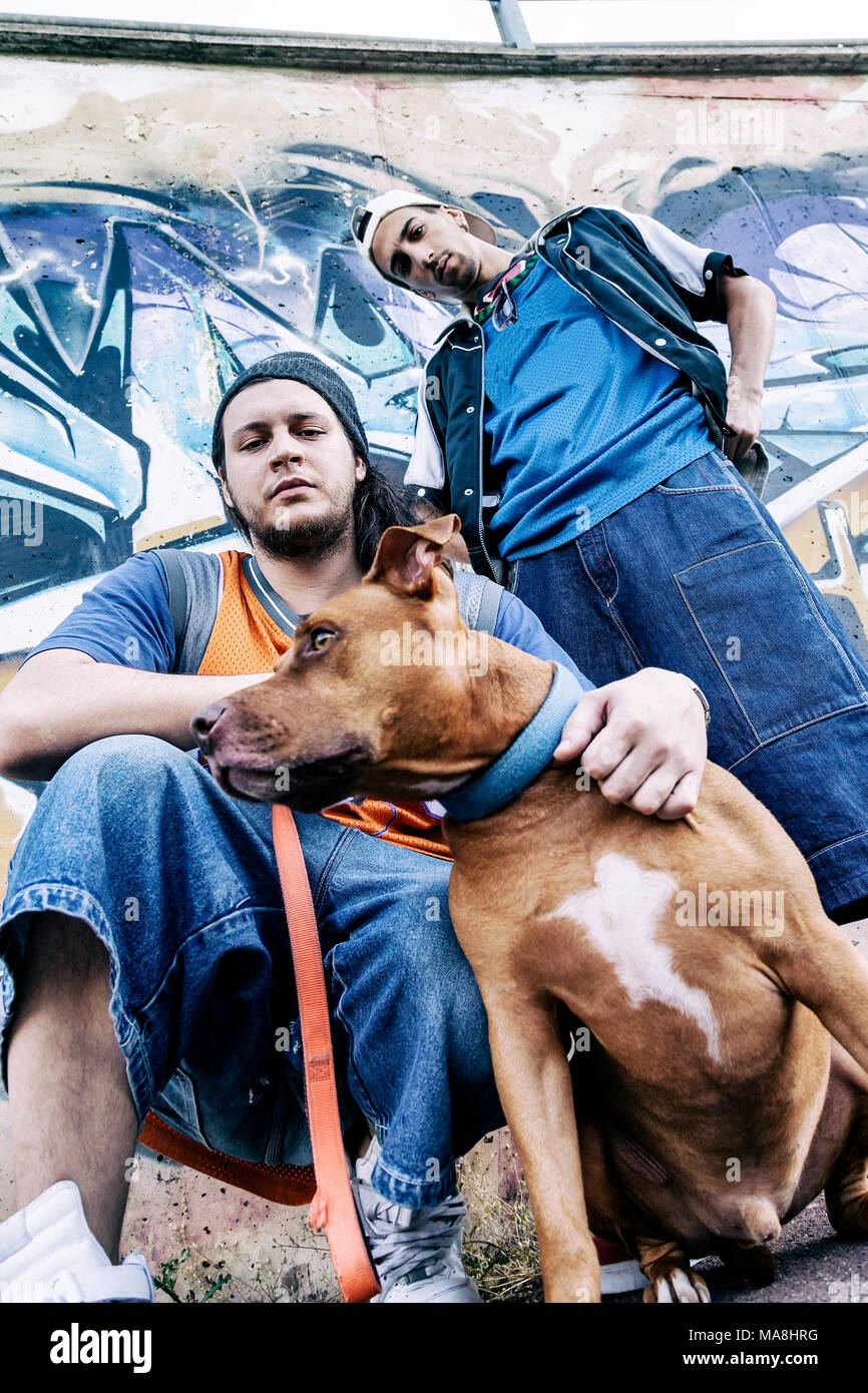 two rap singers with a dog in a subway with graffiti in the background ...