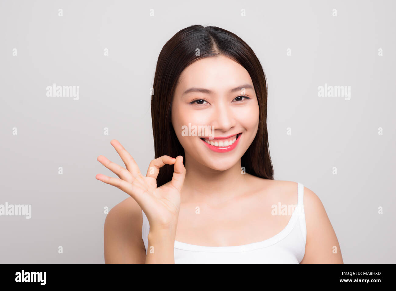 Portrait of a beautiful young woman with clean skin gesture ok sign ...