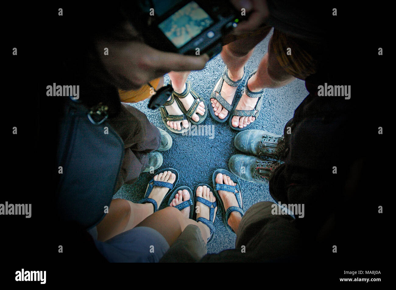 Top view of friends legs and feet in sandals and boots standing in ...