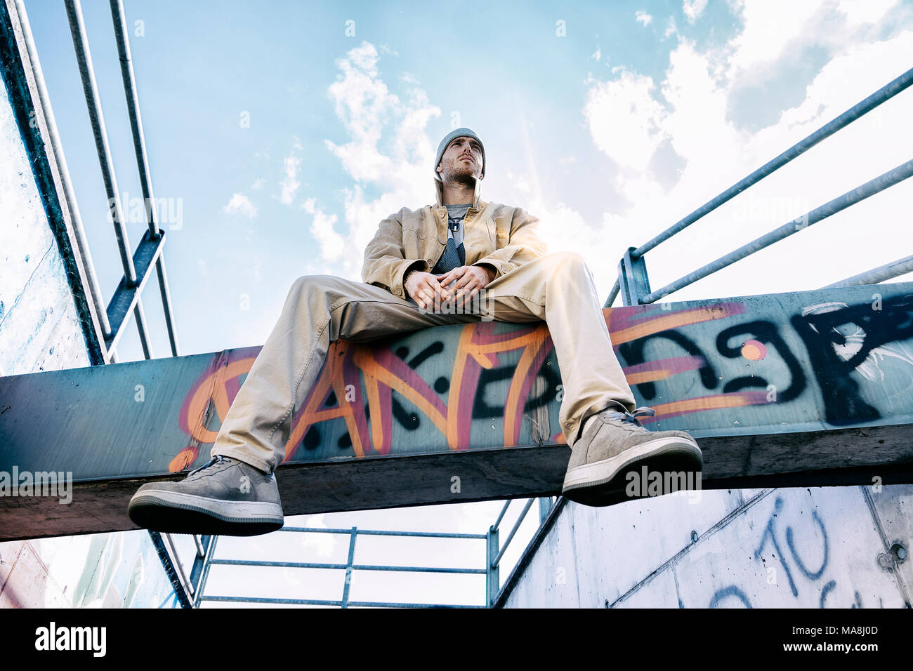 a rap singer on a concrete beam in a subway with graffiti in the ...