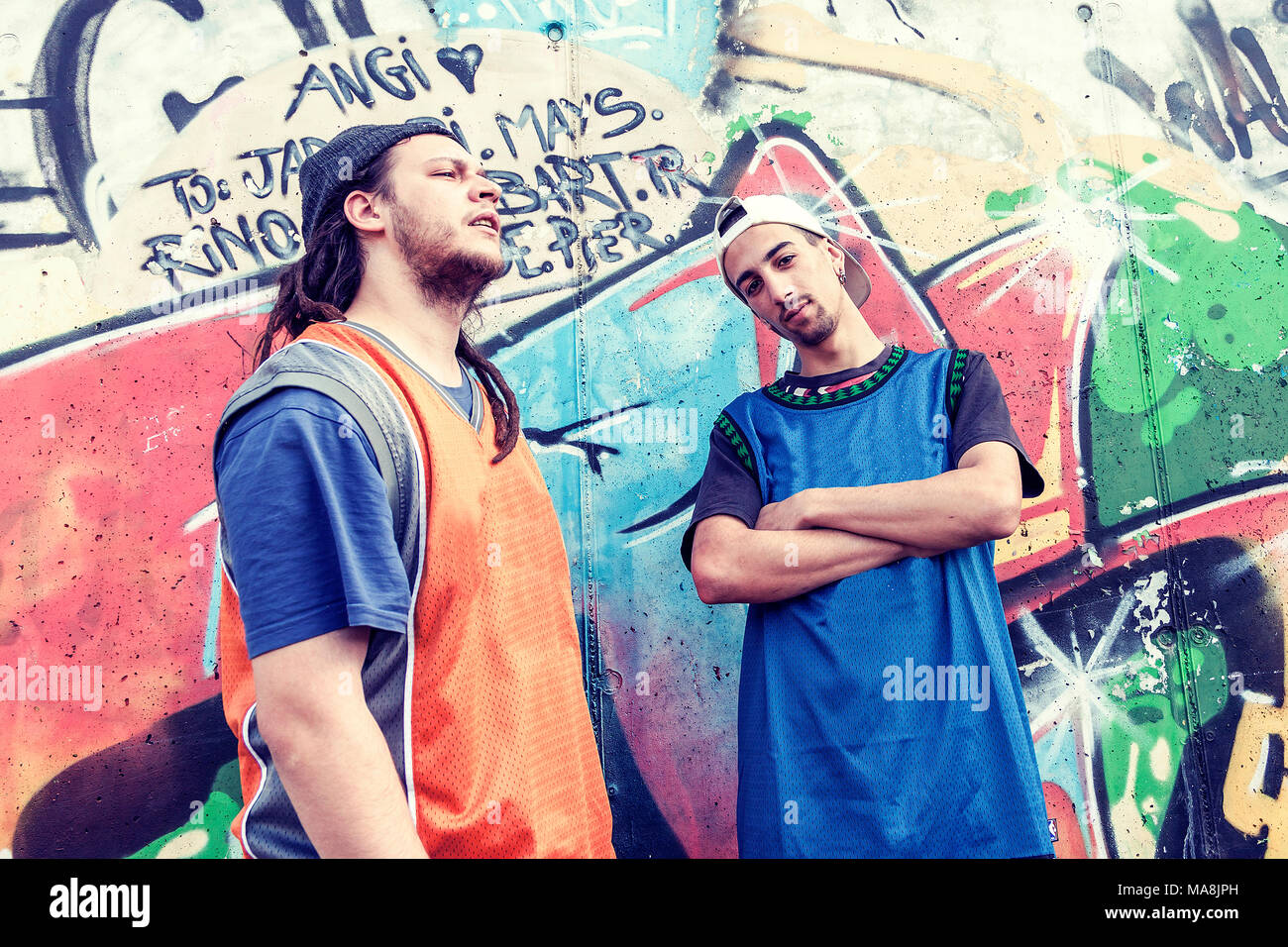 two rap singers in a subway with graffiti in the background posing in ...
