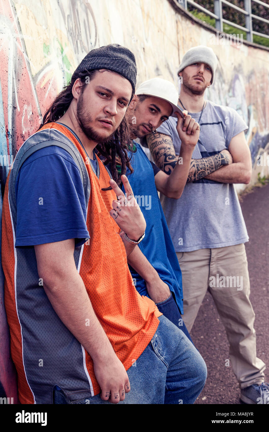 three rap singers in a subway with graffiti in the background posing in ...