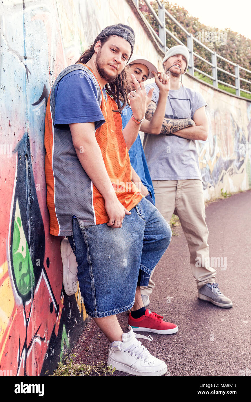 three rap singers in a subway with graffiti in the background posing in ...