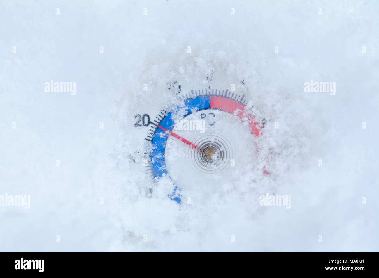 Thermometer with celsius scale placed in a fresh snow showing sub-zero ...