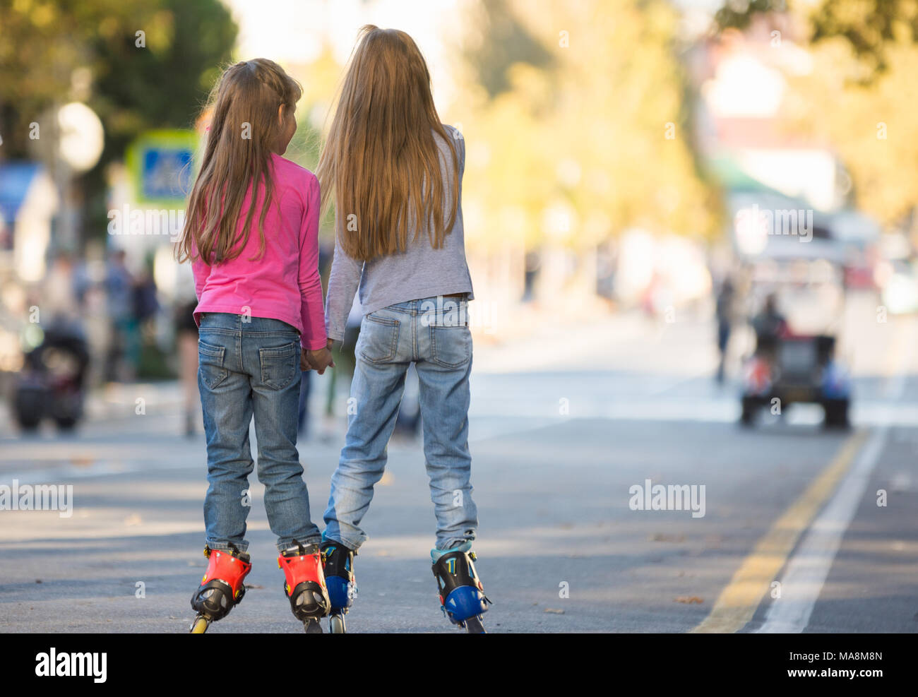 Two girls girlfriends rollerblading on the mall, rear view Stock Photo ...