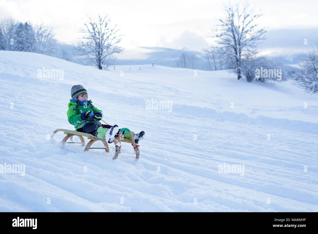 Little Boy sitting on wooden sled in snow, sledding Stock Photo - Alamy