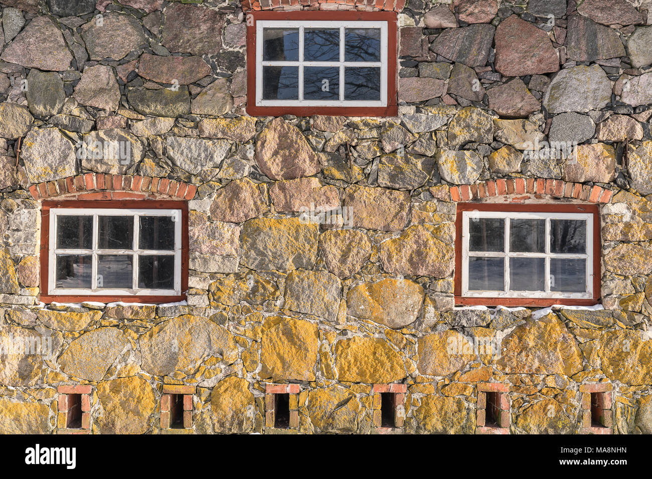 Stone wall texture and windows with red frames, natural background ...