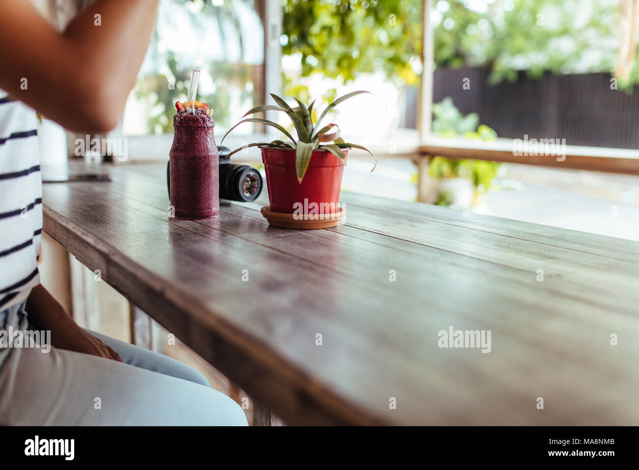 Woman sitting near a window with a smoothie on the table. Smoothie jar ...