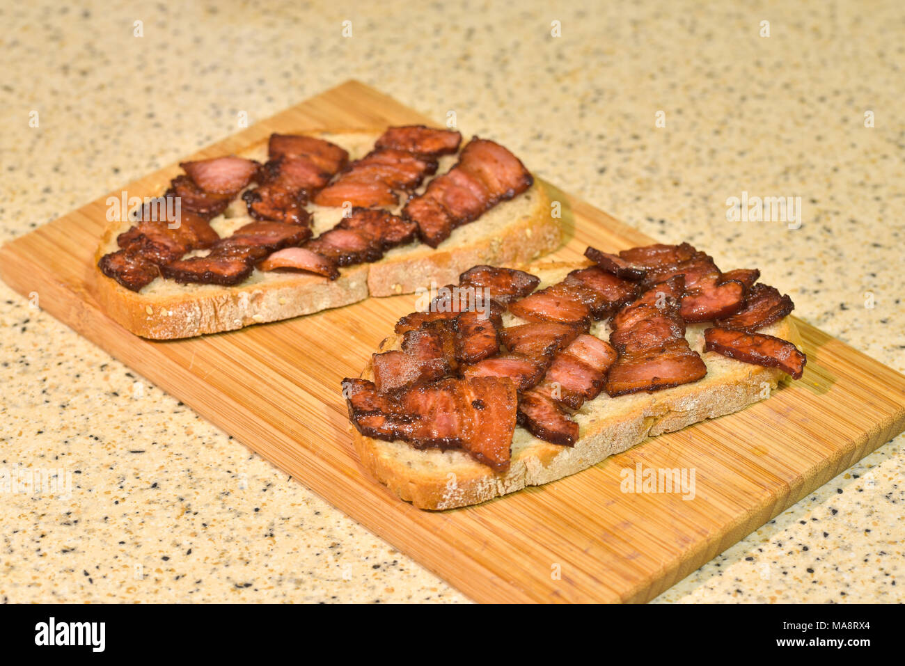 Fried bacon on slice of bread on chopping block Stock Photo - Alamy