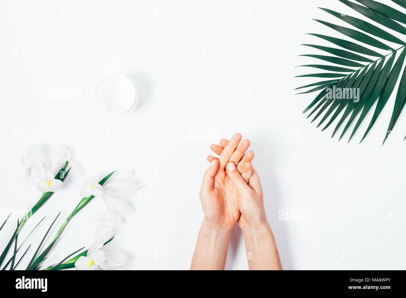 Woman applying hand cream among tropical flowers on white background ...