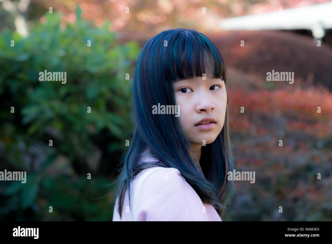 Portrait of beautiful young asian woman with blue and green hair in a ...