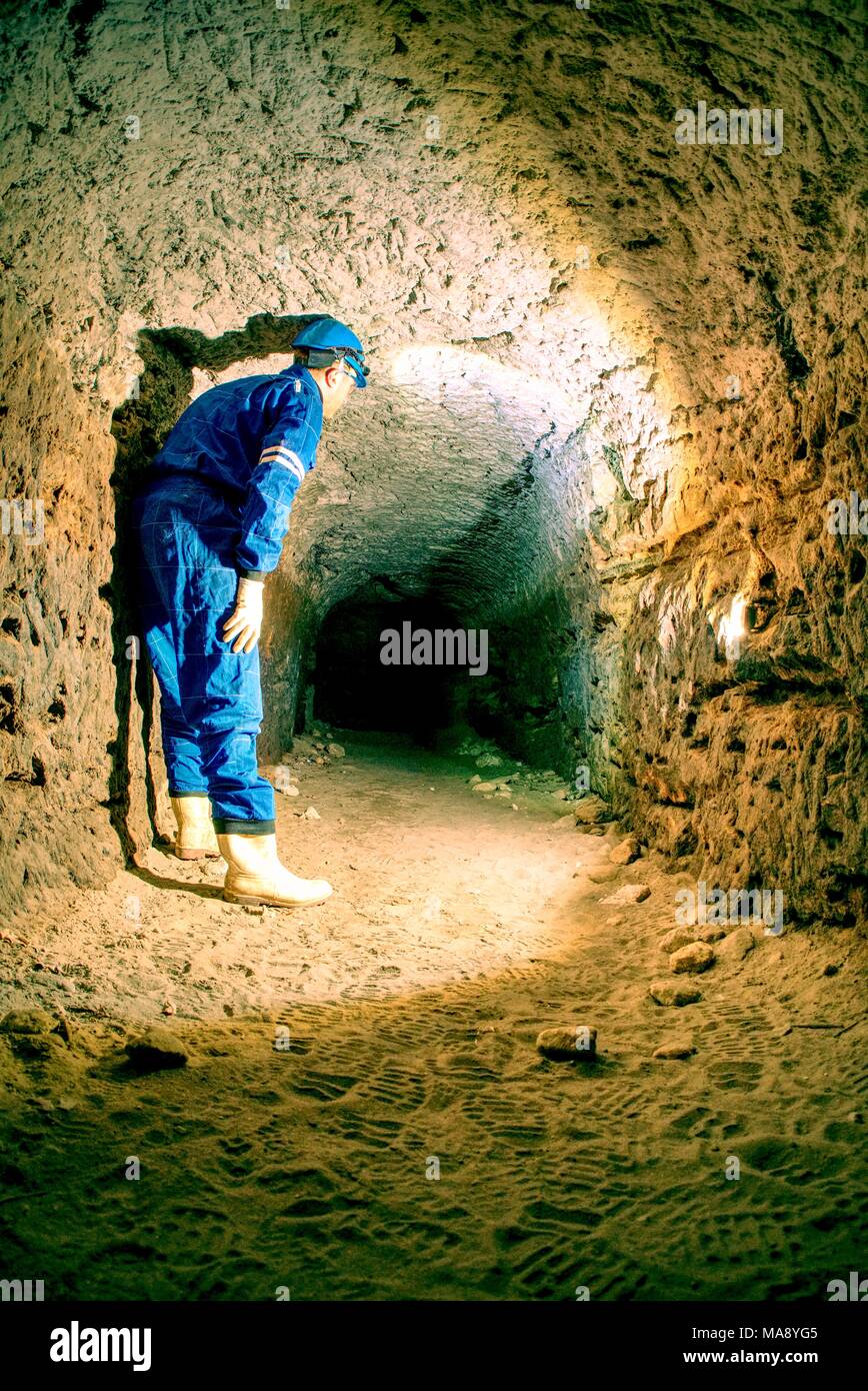 Workerman with helmet and protective suit using glowes and head lamp ...