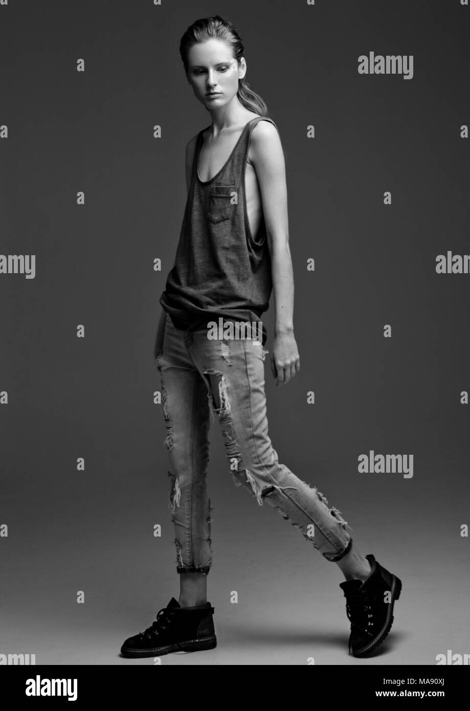 Model test with young beautiful fashion model wearing t-shirt on black ...