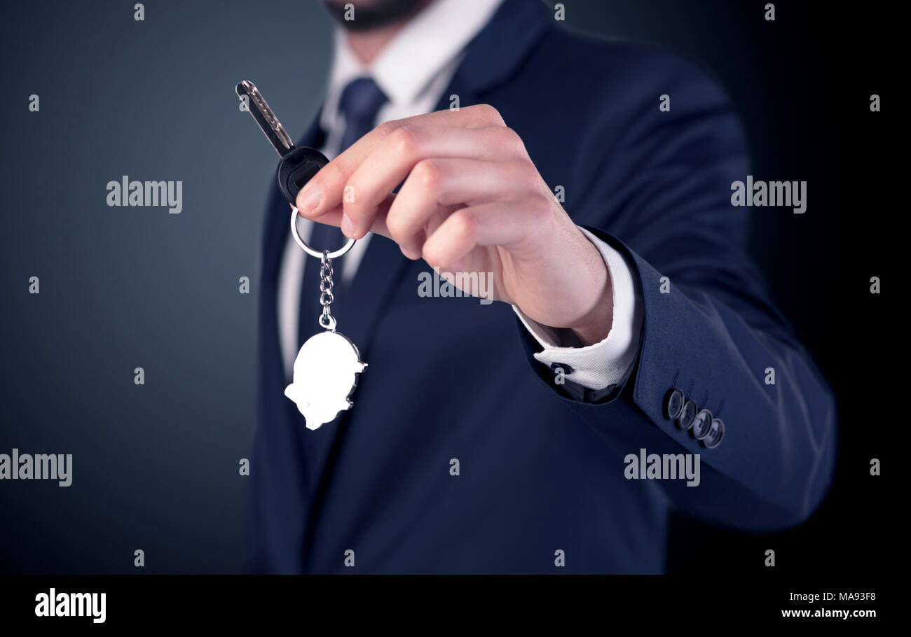 Young businessman hand over keys with empty dark background Stock Photo ...