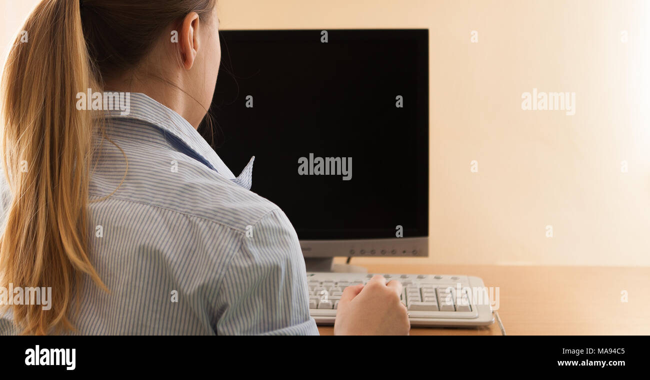 Young woman working on a desktop computer at her desk in the office ...