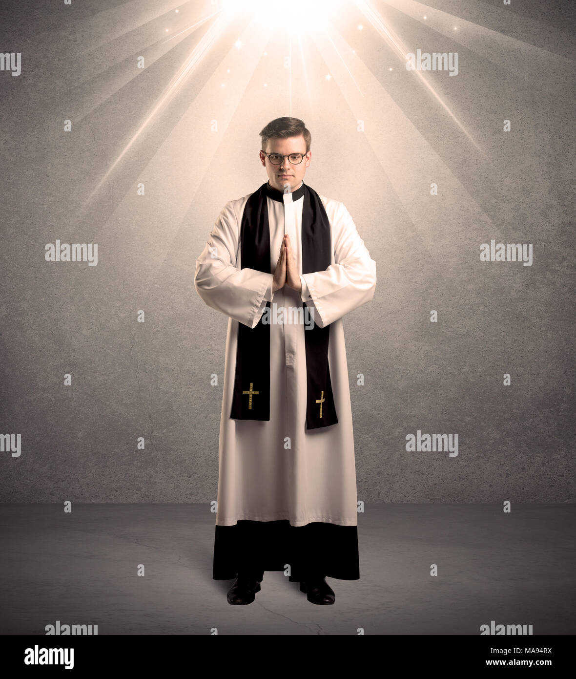 A male religious young priest in black and white dress giving his ...