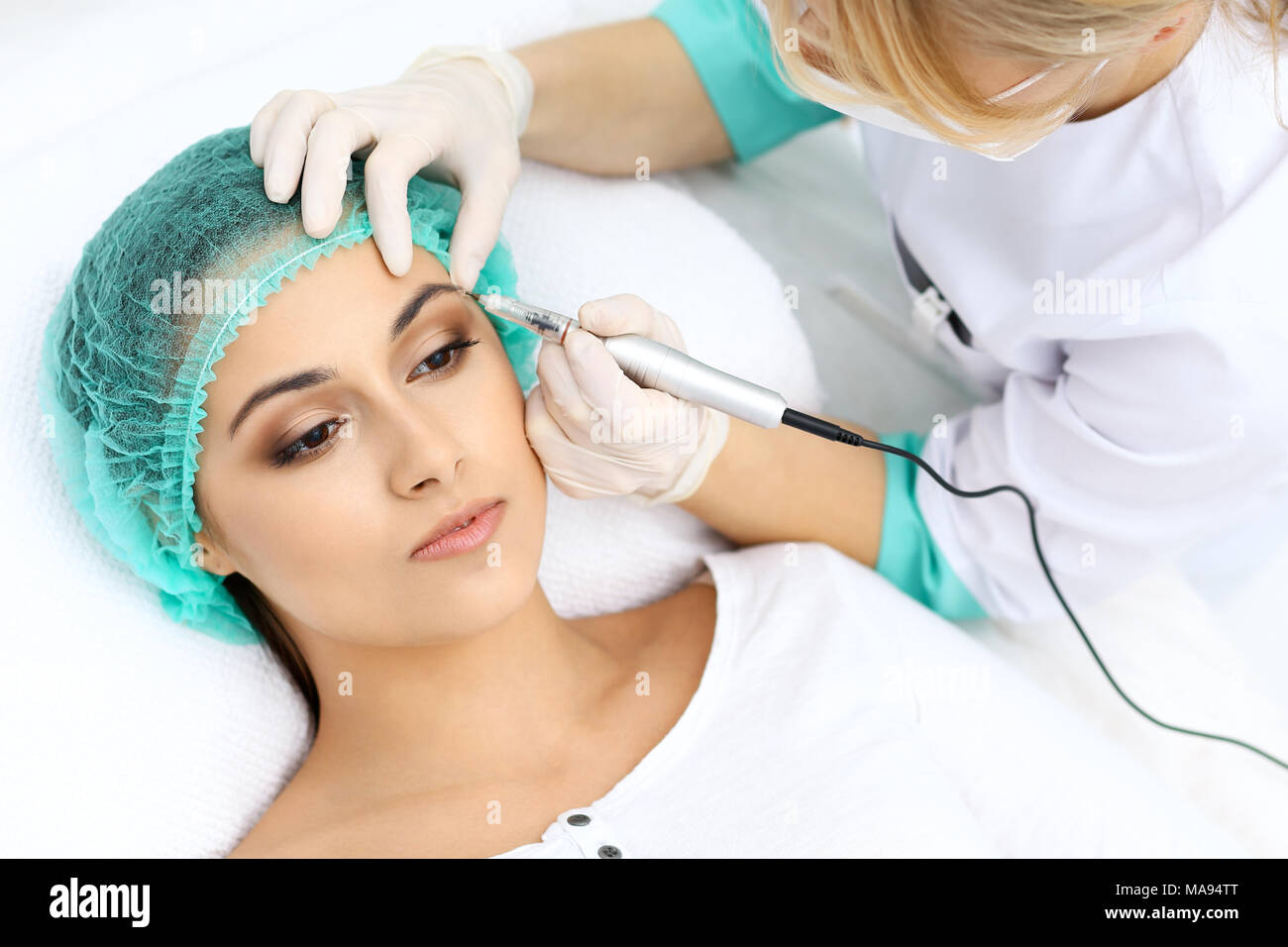 Professional beautician doing eyebrow tattoo at woman face. Permanent ...