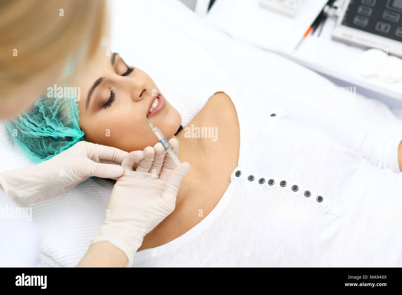 Professional cosmetologist making injection in face, lips. Young woman ...