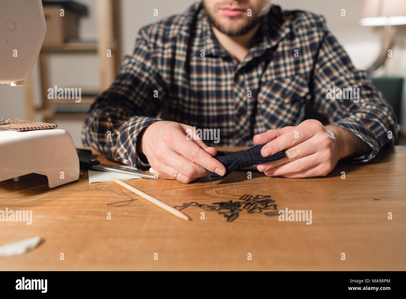with a needle and thread in hand. Good looking young man working as a ...