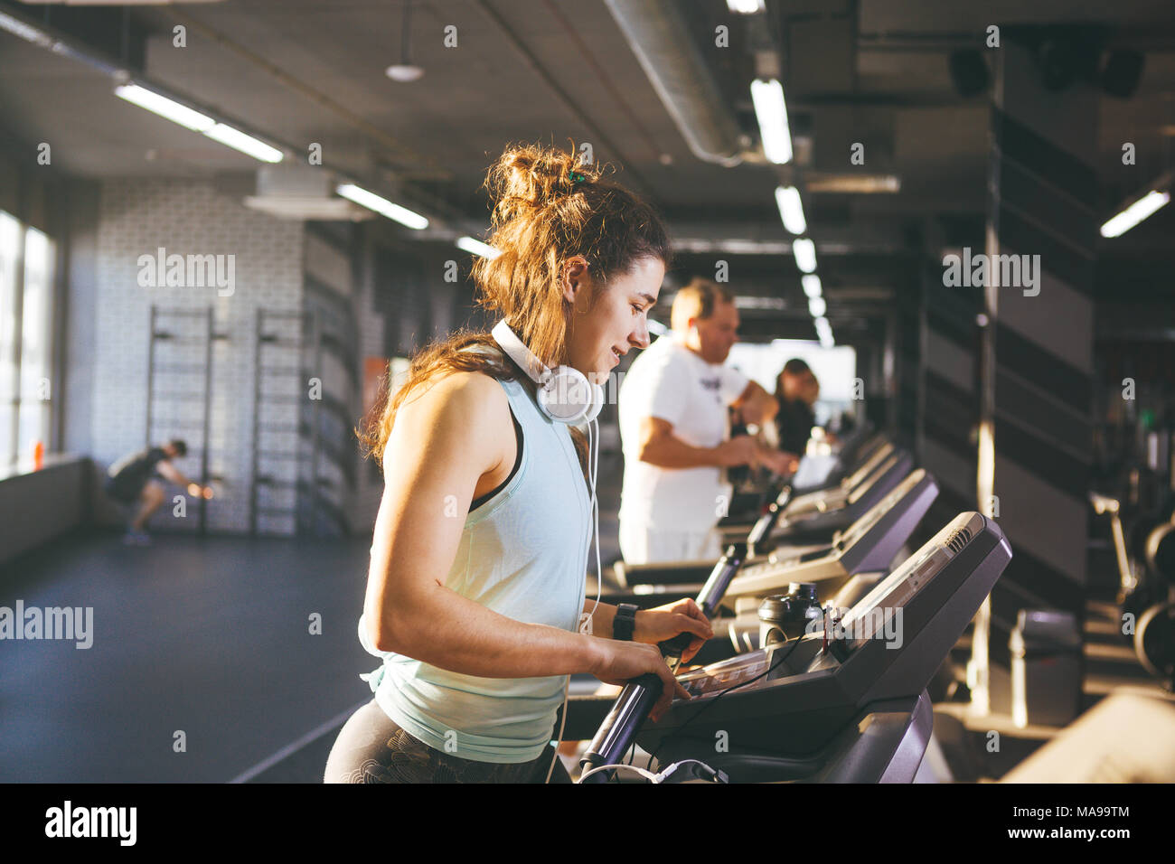 beautiful young woman with lush curly hair in vest and leggings runs in ...