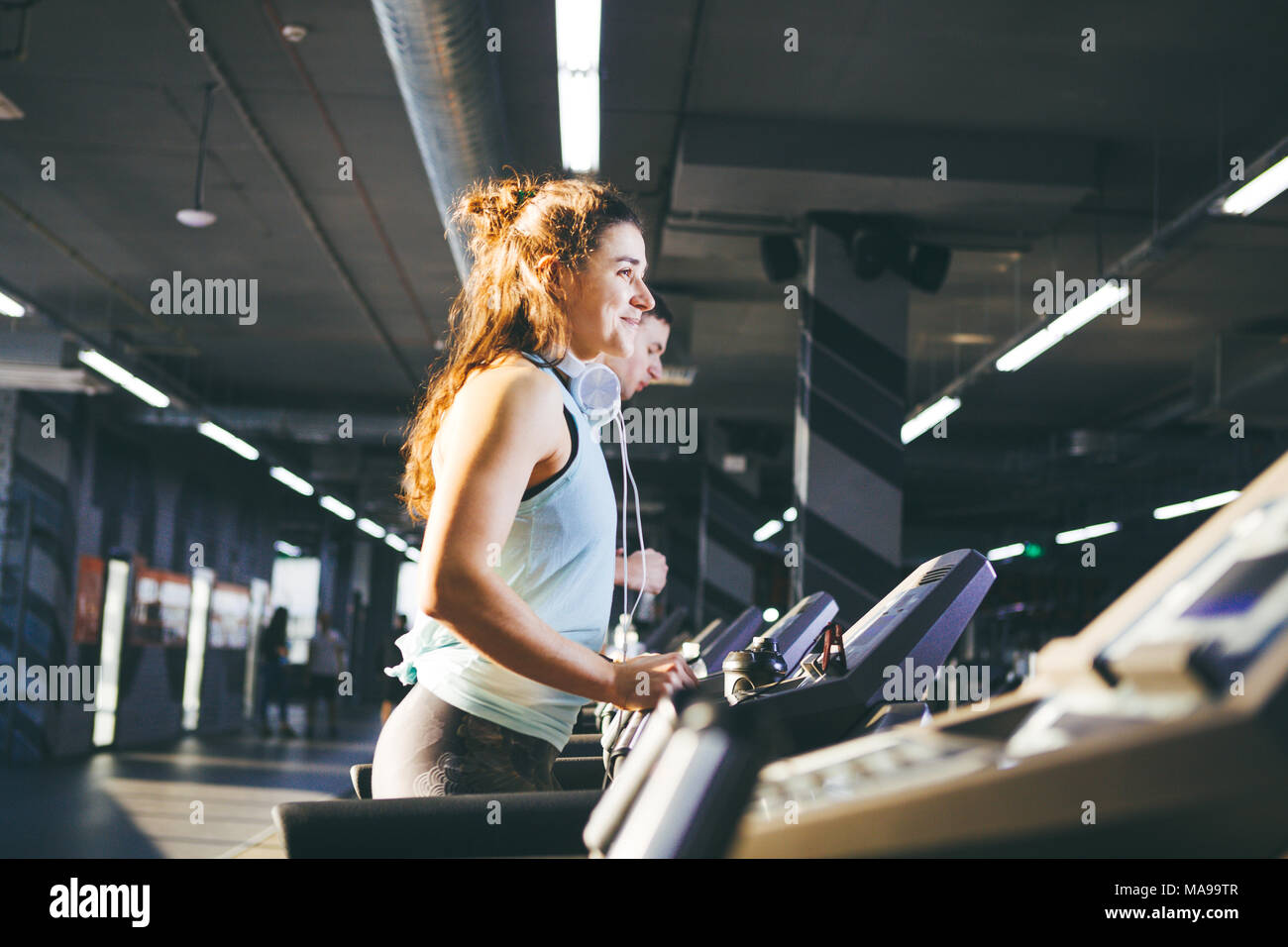 beautiful young woman with lush curly hair in vest and leggings runs in ...