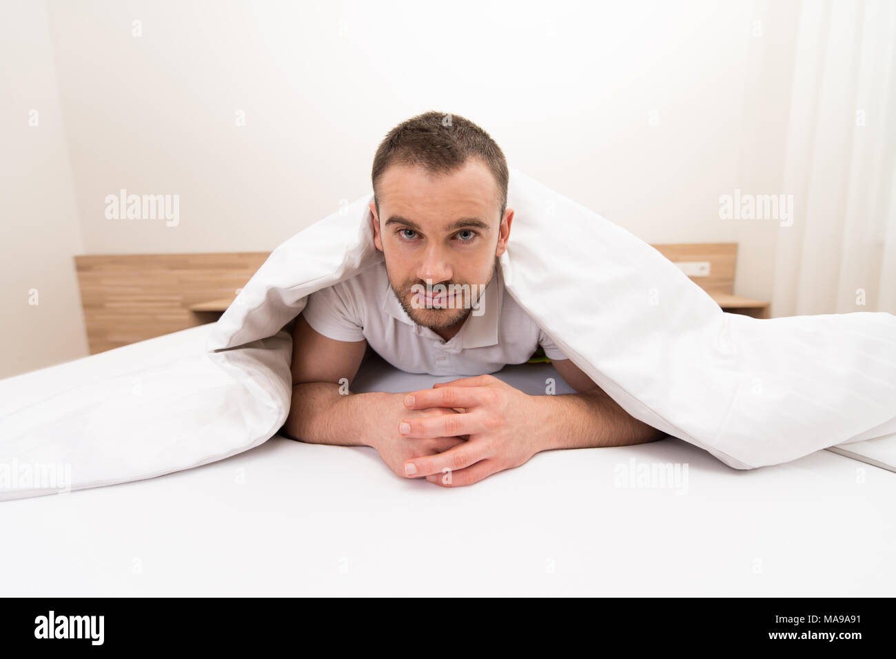 Portrait of a Man Lying Under a Blanket at Home Stock Photo - Alamy