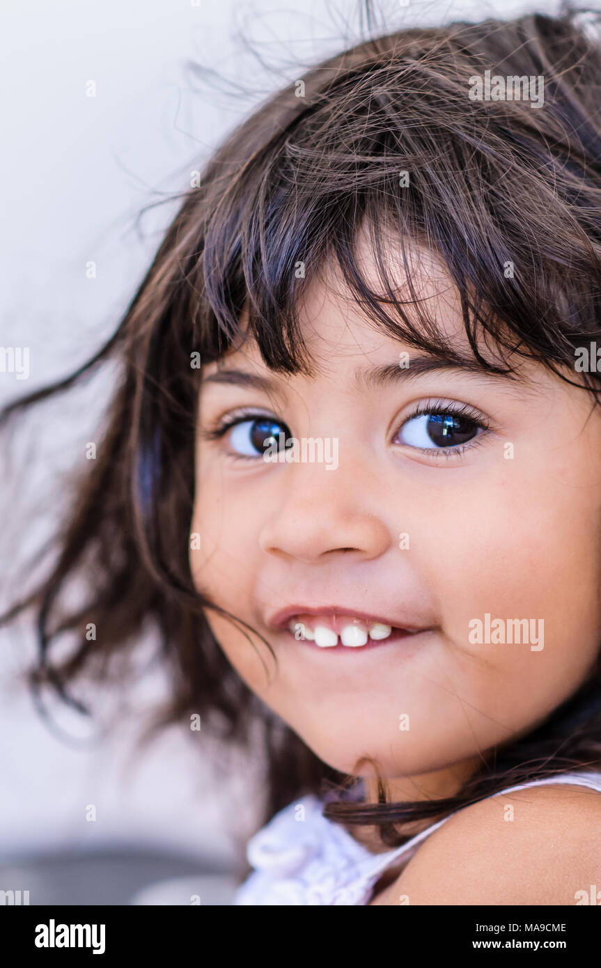 Mexican little girl at school smiling with sneaky look and teeth out ...
