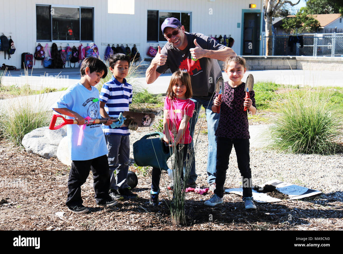 Kindergarten and first grade students learn how to mulch, dig Stock ...