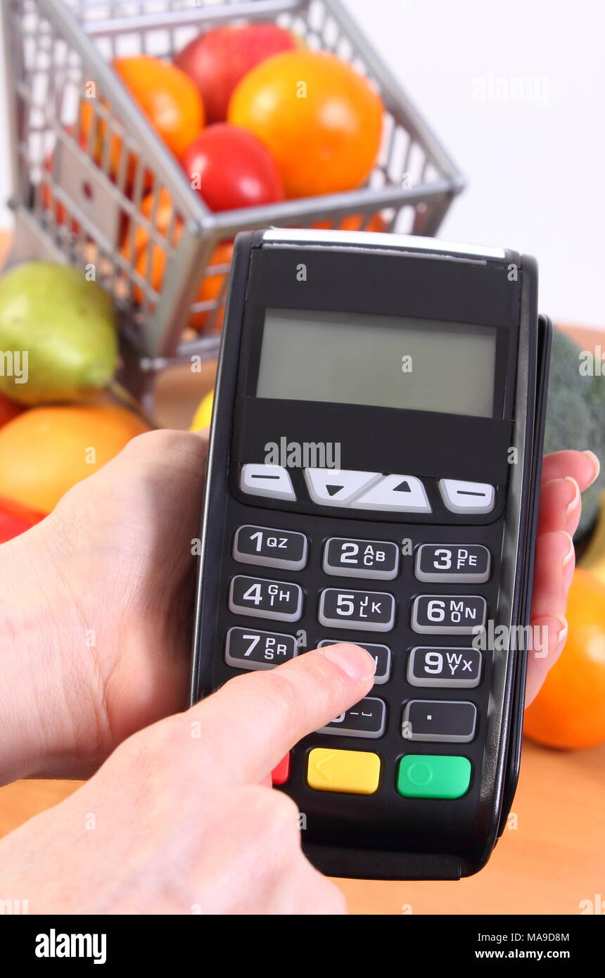 Hand using payment terminal, enter personal identification number ...