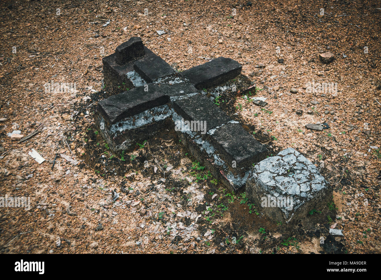 Detail of a grave in a cemetery. Old ruined cross on the ground ...