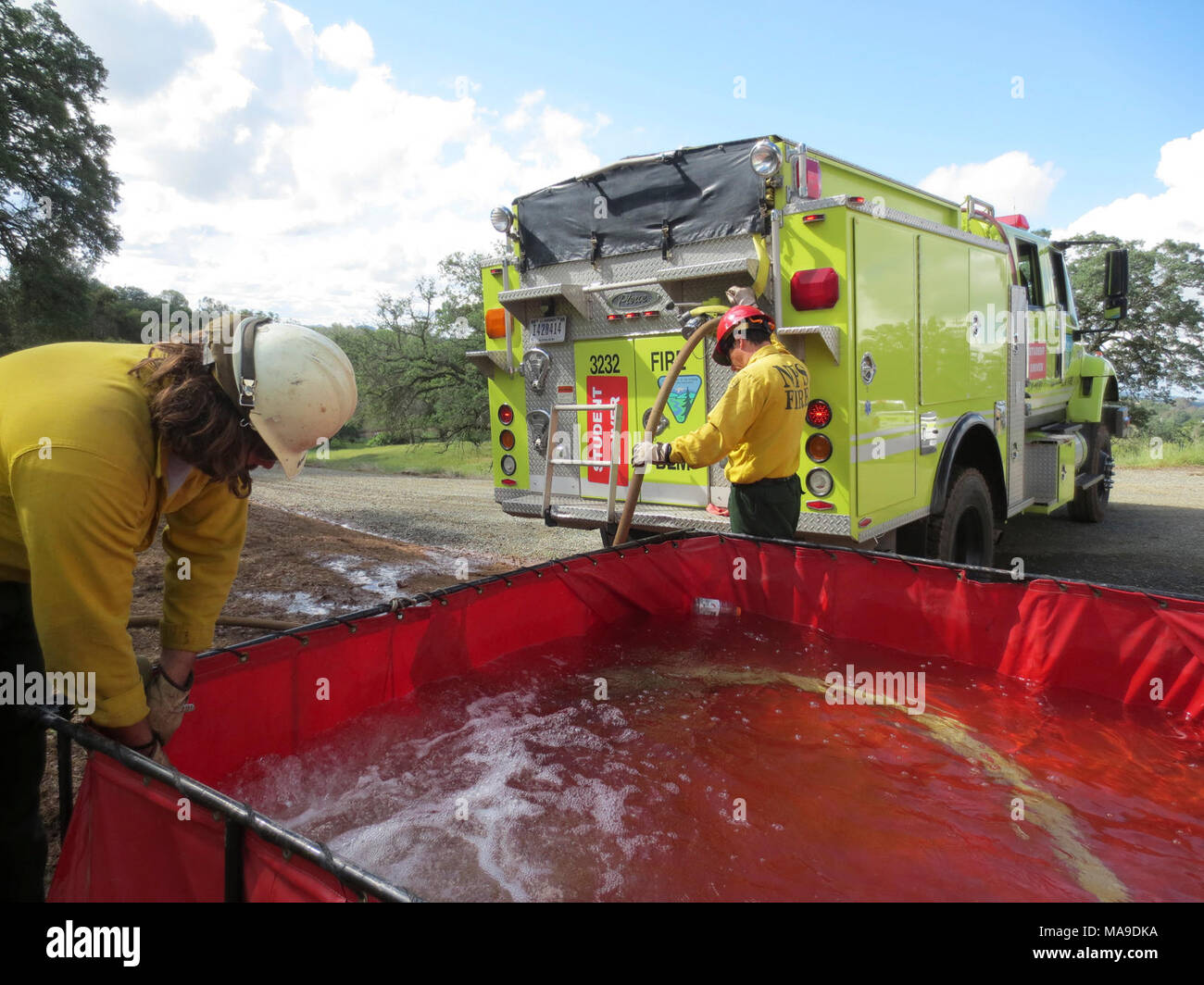 Portable Water Tank. Wildland firefighters fill a large portable water ...