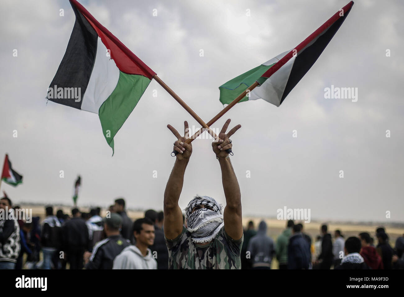 A Palestinian protester flashes the victory sign and hold his country's ...