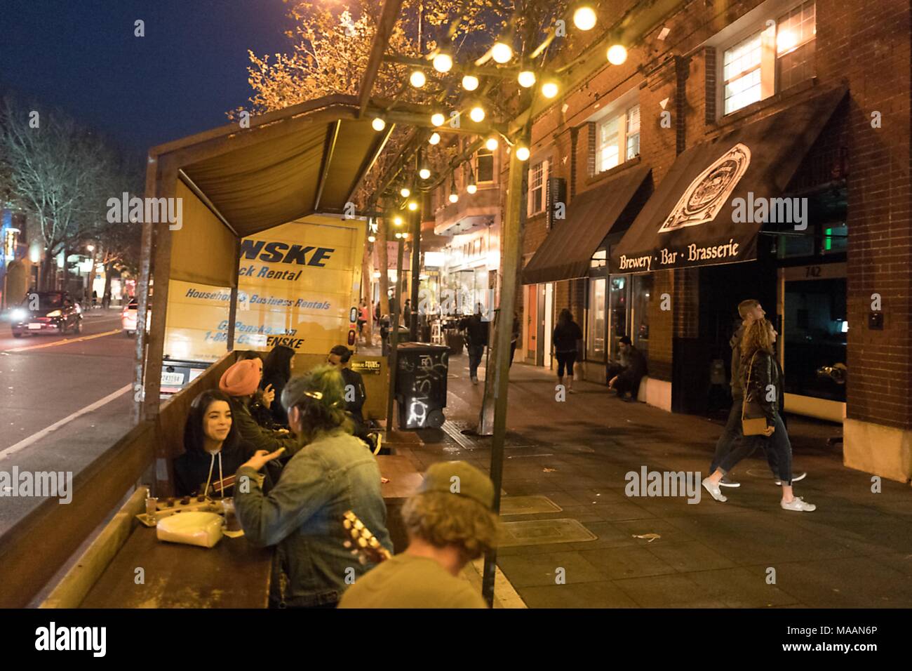 People sit and talk at a public parklet on Valencia Street in the ...