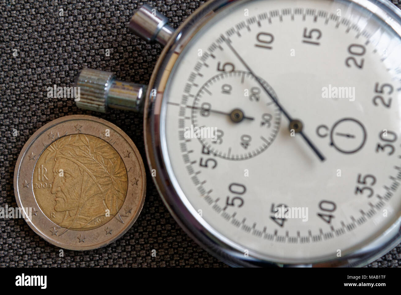 Euro coin with a denomination of 2 euro (back side) and stopwatch on ...
