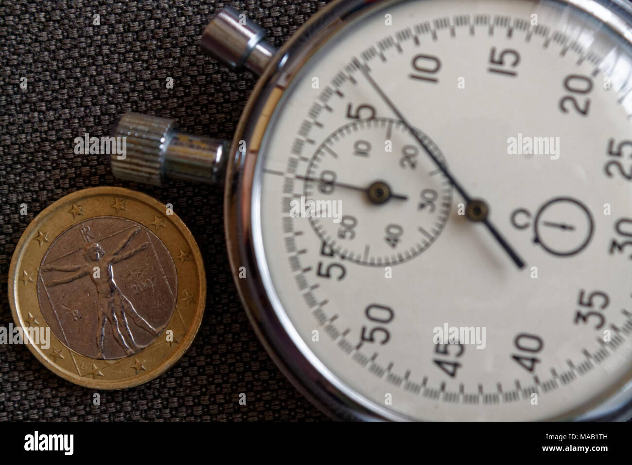 Euro coin with a denomination of 1 euro (back side) and stopwatch on ...
