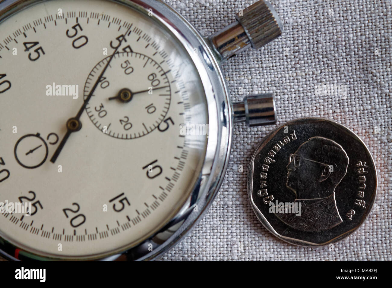Thai coin with a denomination of 5 baht (back side) and stopwatch on ...