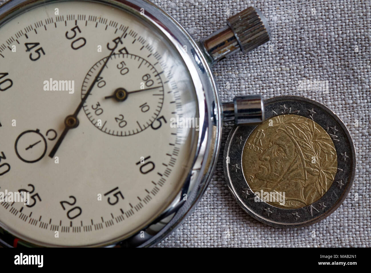 Euro coin with a denomination of 2 euro (back side) and stopwatch on ...