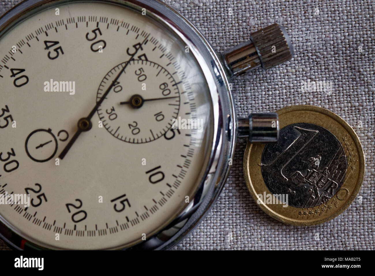 Euro coin with a denomination of one euro (back side) and stopwatch on ...