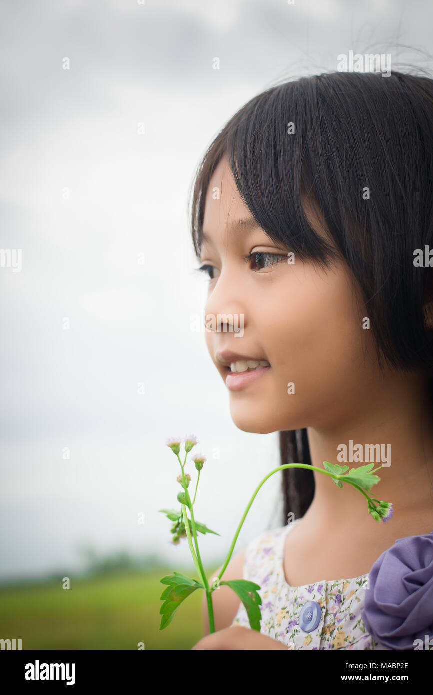 Portrait of Little cute asian girl holding flower among the purple ...
