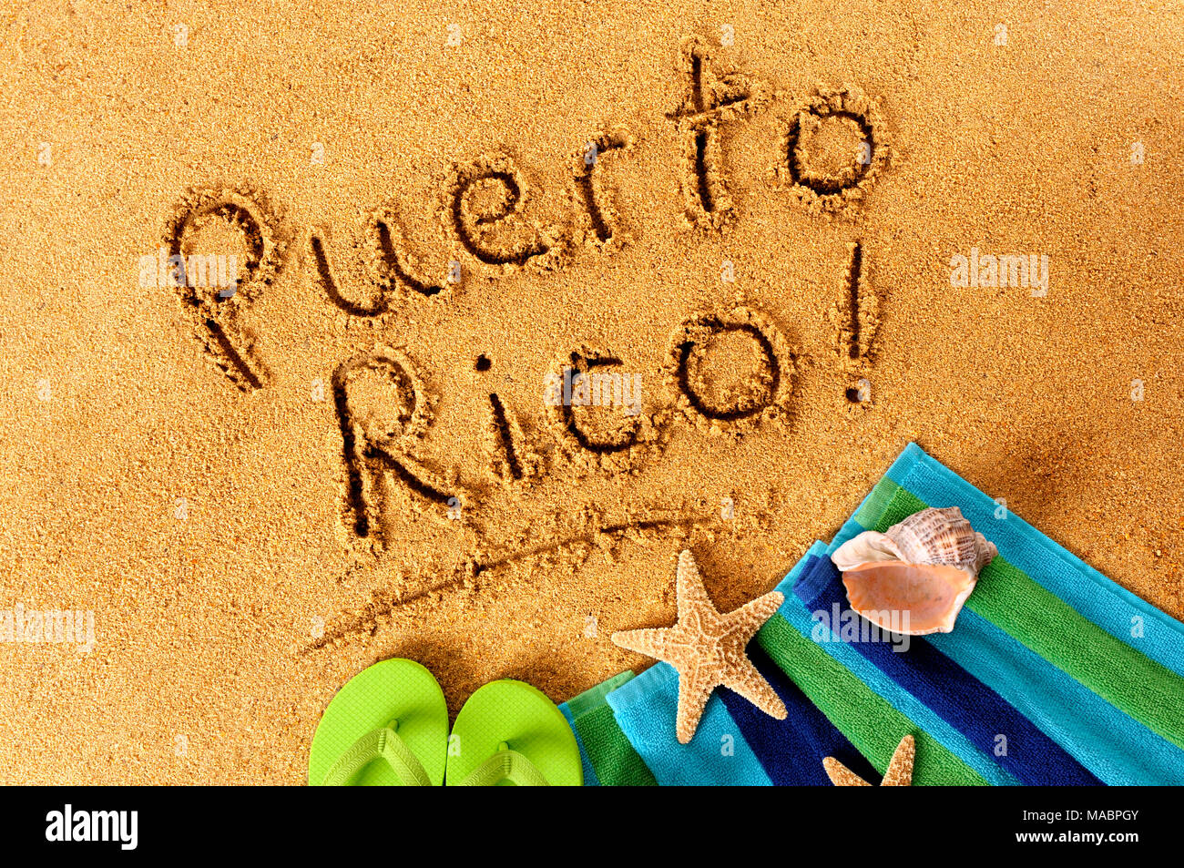 The words Puerto Rico written on a sandy beach, with beach towel ...