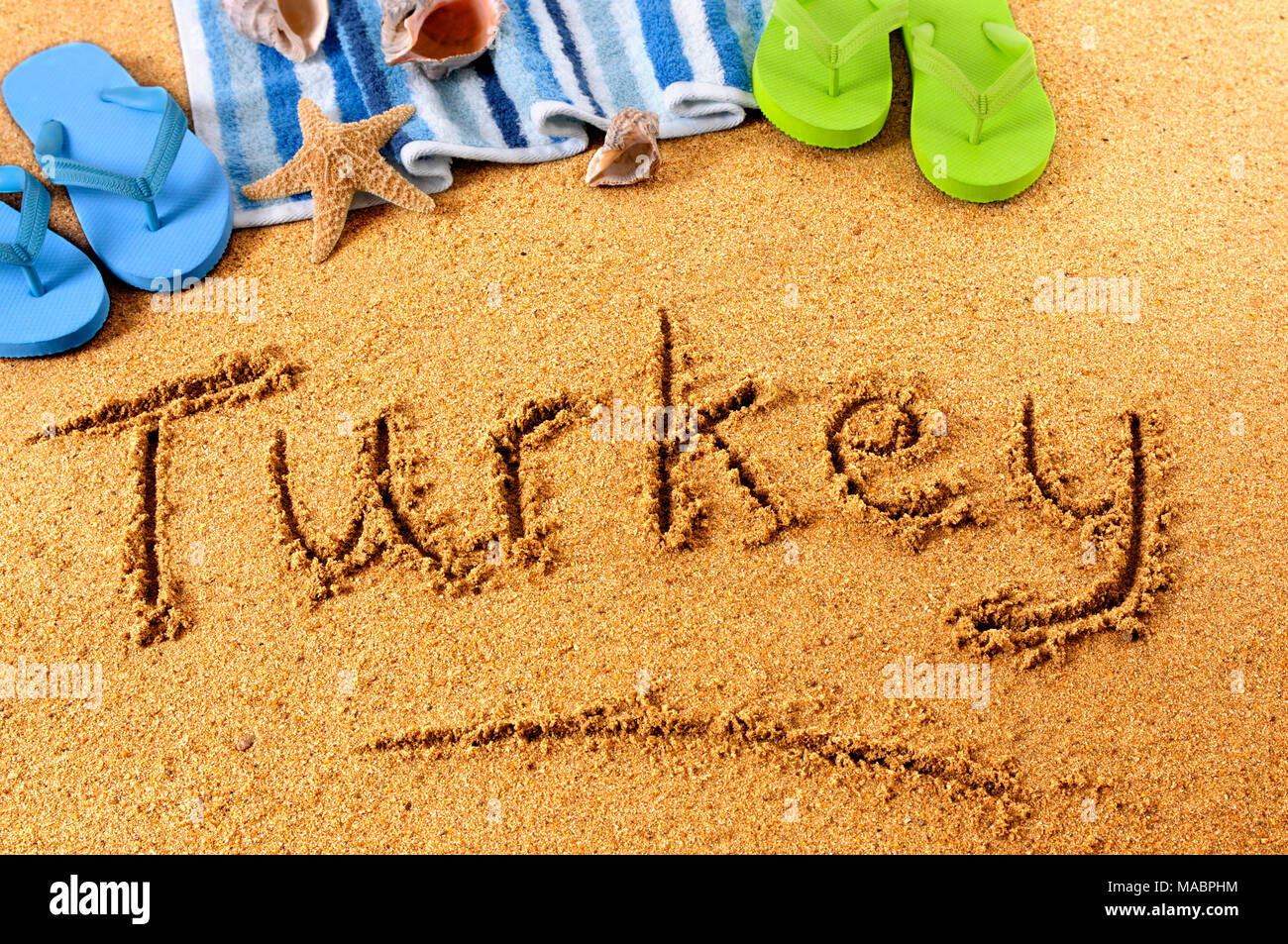 The word Turkey written on a sandy beach, with beach towel, starfish ...