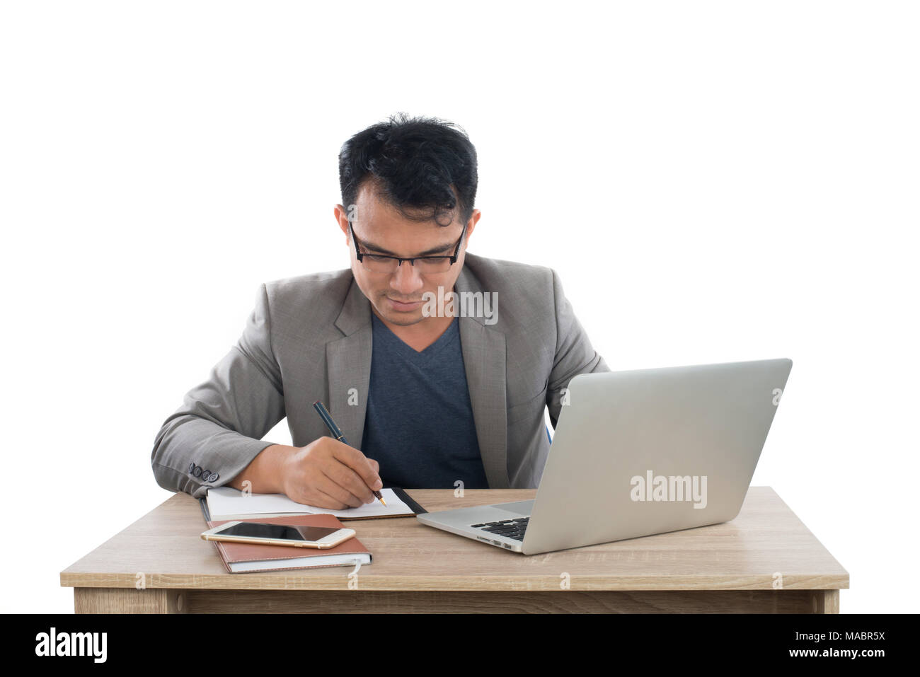 businessman writing notes on a writing pad while sitting at his desk ...