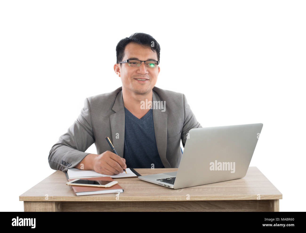 businessman writing notes on a writing pad while sitting at his desk ...
