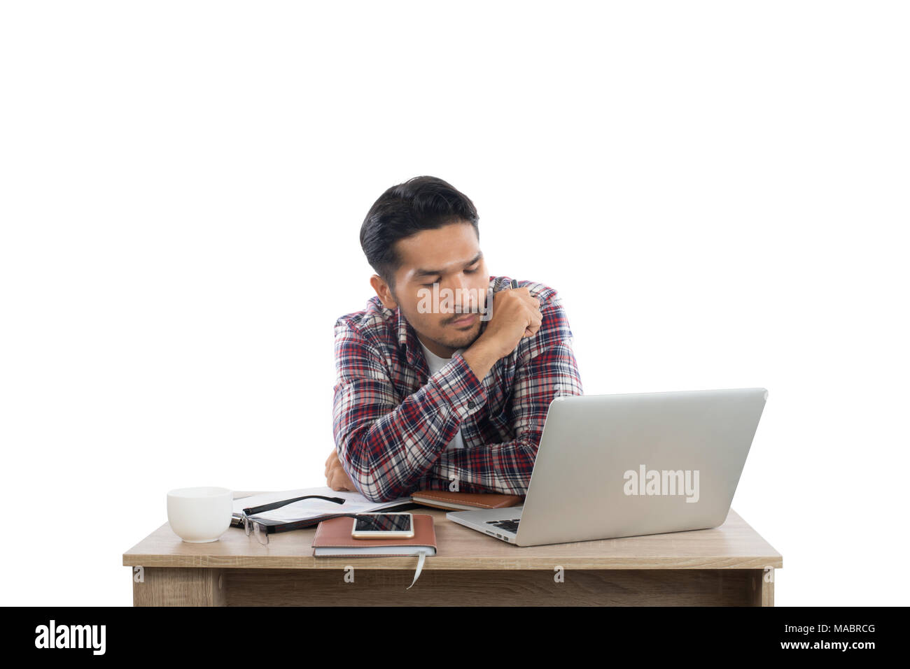 Thoughtful young man holding pen looking at notepad while sitting at ...